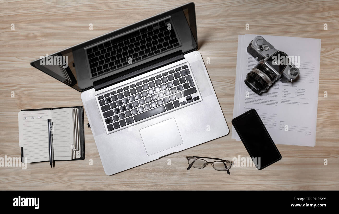 Wooden photographer desk table with camera, laptop, notebook, pen ...
