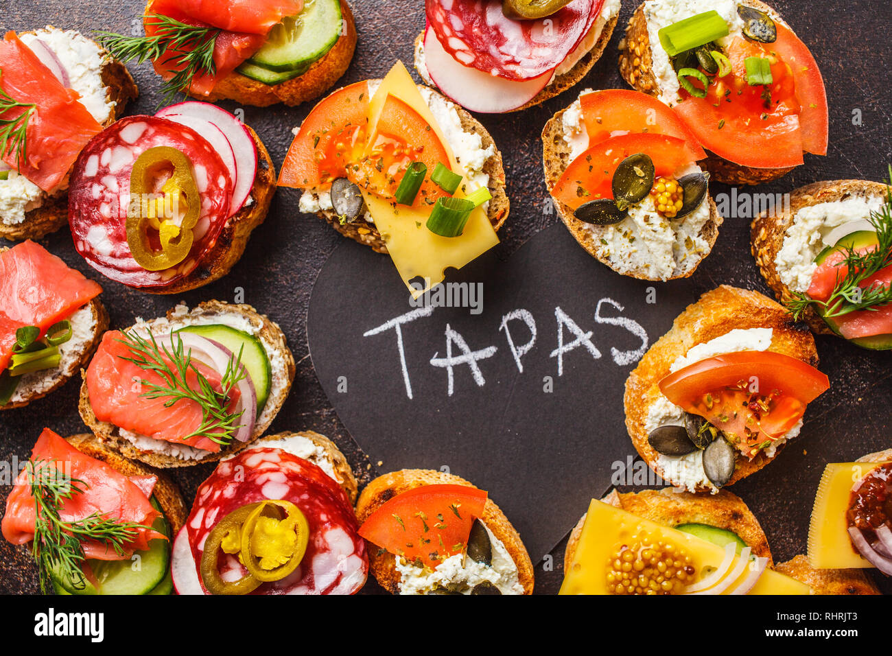 Assorted spanish tapas with fish, sausage, cheese and vegetables. Dark ...