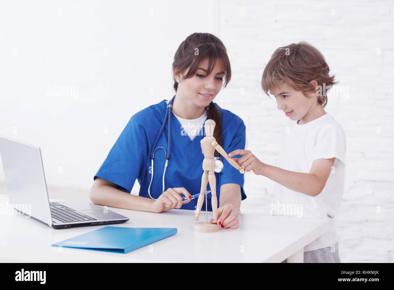 Doctor explain medicine to child using wooden doll Stock Photo - Alamy