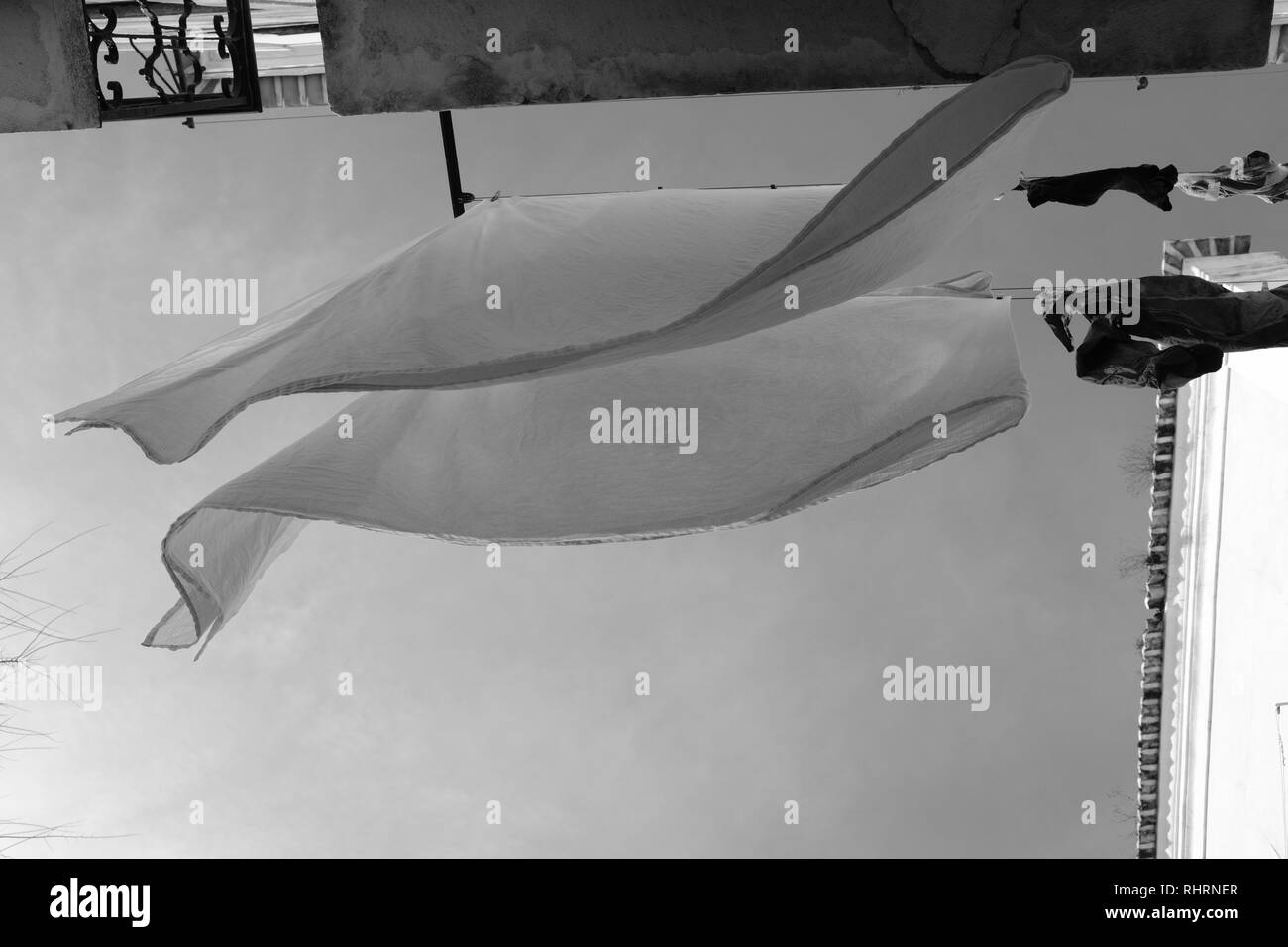 Pure white sheets hanging out to dry on a windy day on a washing line ...