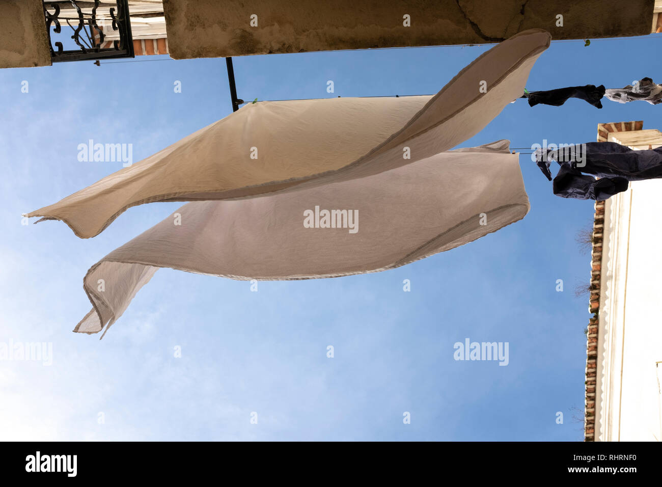 Pure white sheets hanging out to dry on a windy day on a washing line ...