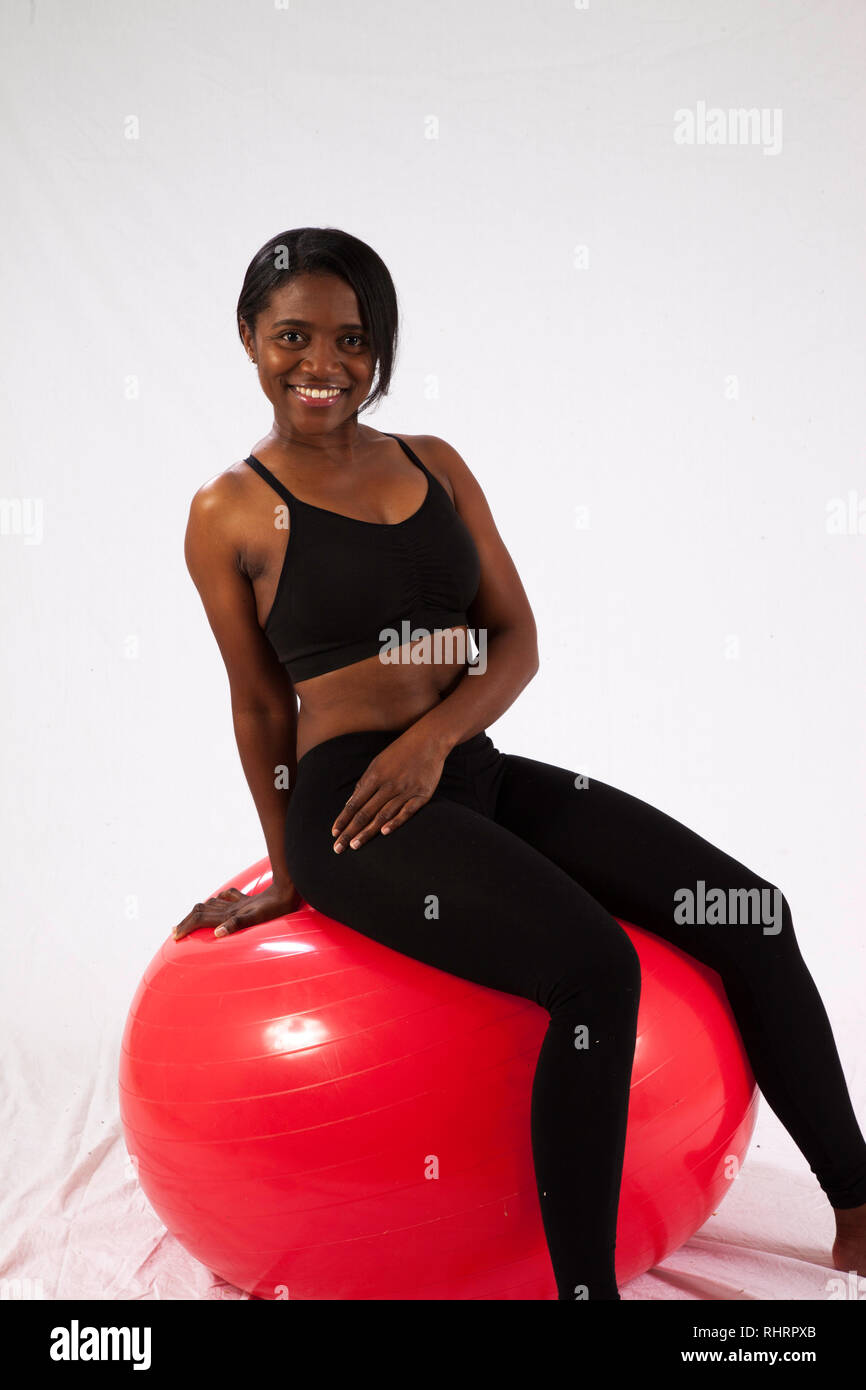 Happy Black woman on a red exercise ball Stock Photo - Alamy