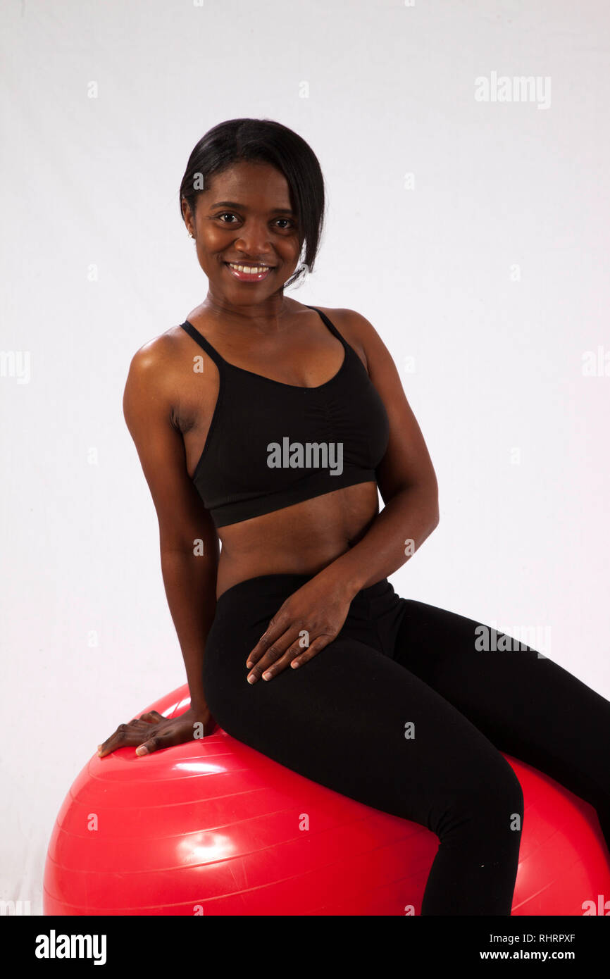 Happy Black woman on a red exercise ball Stock Photo - Alamy