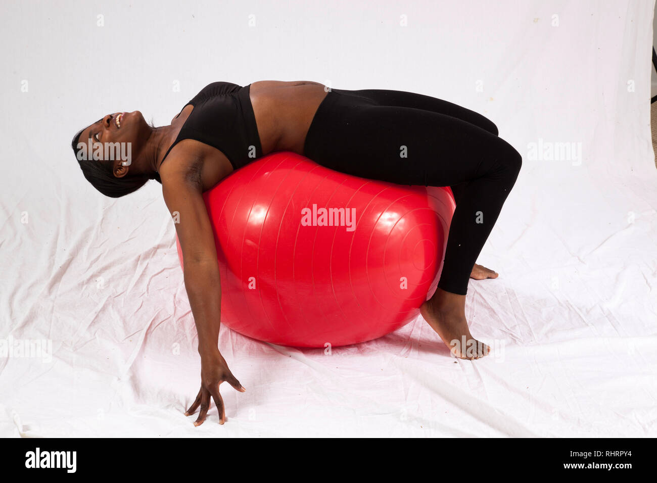 Happy Black woman on a red exercise ball Stock Photo - Alamy