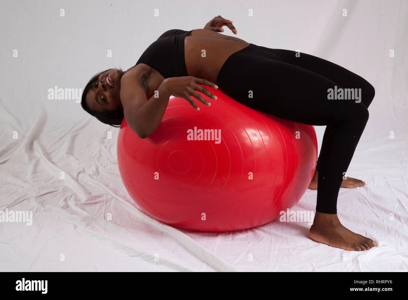 Happy Black woman on a red exercise ball Stock Photo - Alamy