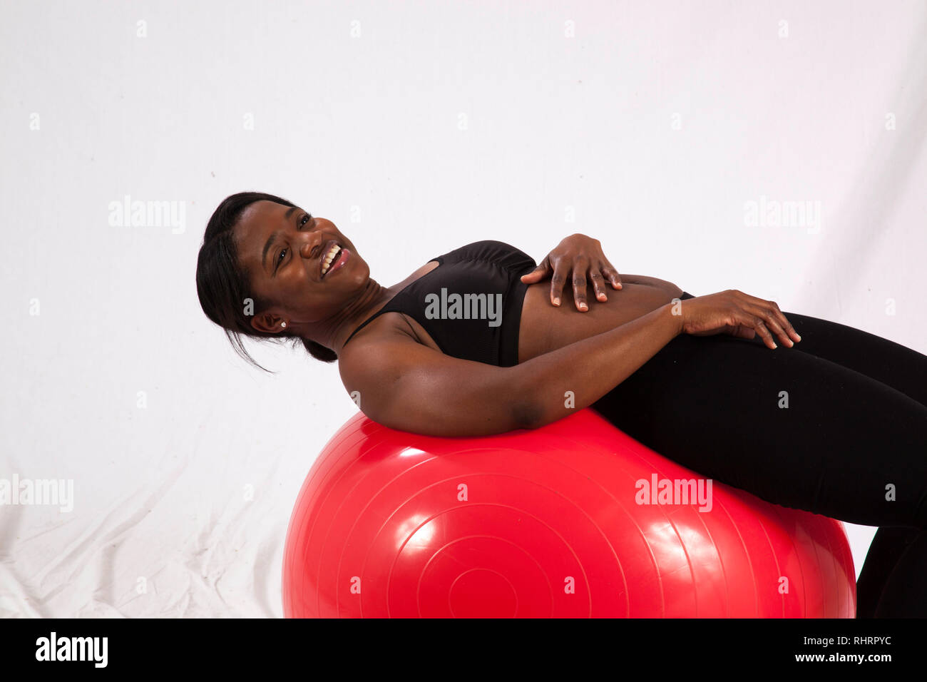 Happy Black woman on a red exercise ball Stock Photo - Alamy
