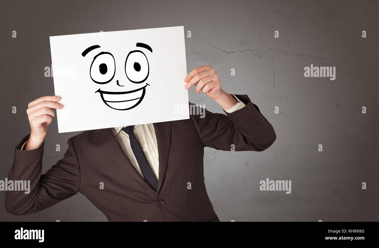 Young student holding a paper with laughing emoticon in front of his ...