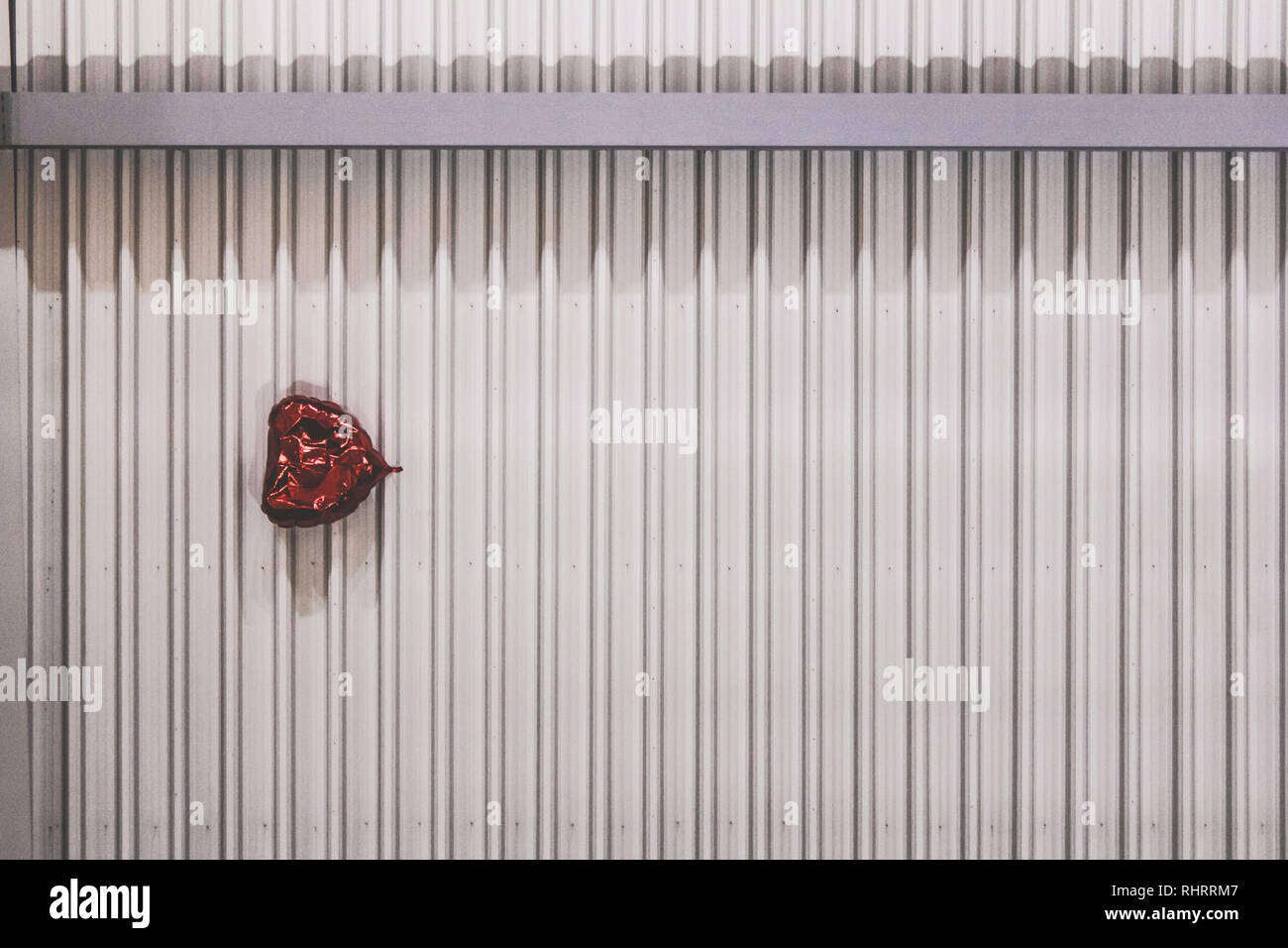 Red damaged heart shaped balloon hanging on an industrial ceiling Stock ...