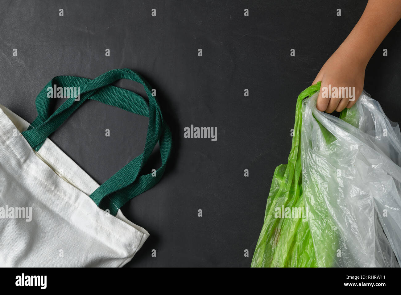 Hand kid holding plastic bags and canvas tote bag on black stone ...