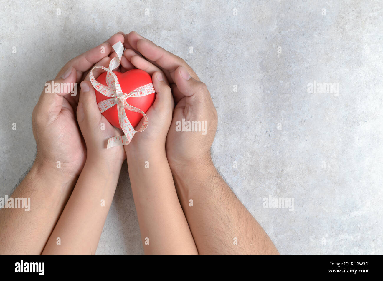 Father and child hands holding red heart on marble background, health ...