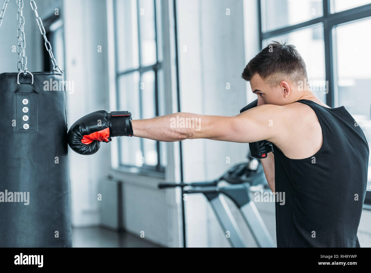 side view of muscular young man boxing with punching bag in gym Stock ...