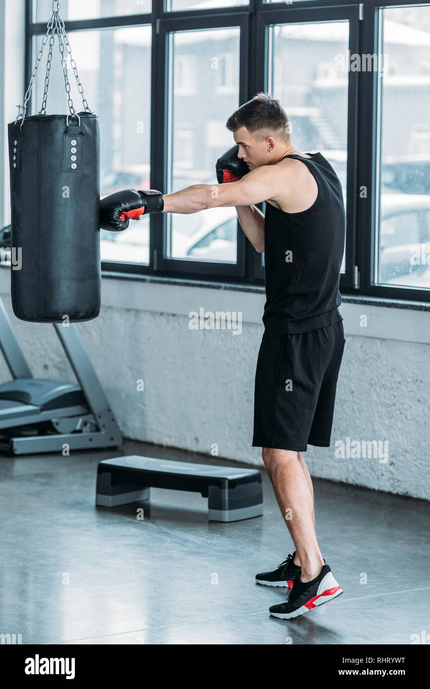 side view of young sporty man boxing with punching bag in gym Stock ...