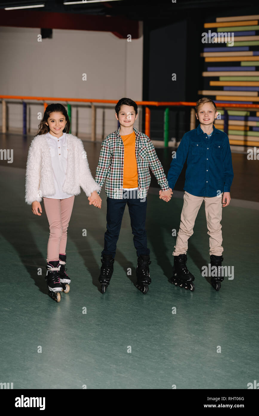Three cute smiling children in roller skates standing with holding ...