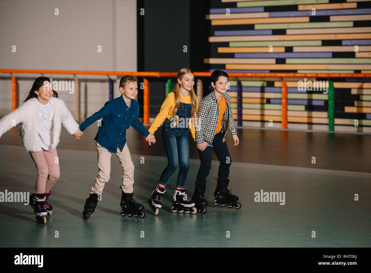 Group of smiling children skating in roller rink with holding hands ...