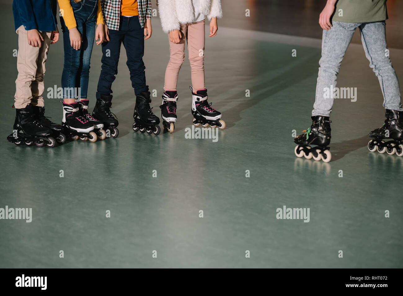 Partial view of children in roller skates listening to trainer ...
