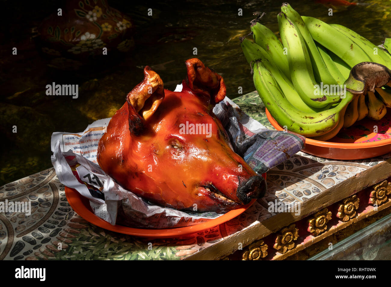 Cambodia, Phnom Penh, Wat Botum, Pig’s head offering on altar outside ...
