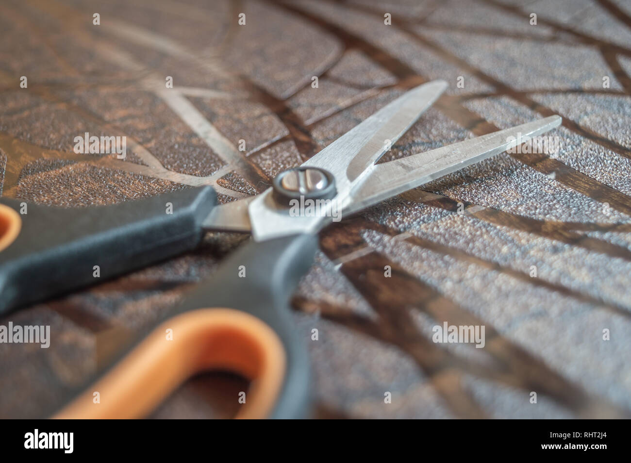 black and orange coloured scissors kept on a textured brown table Stock ...