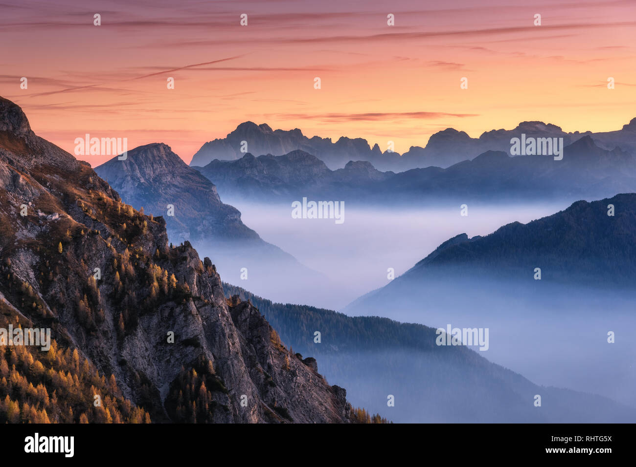 Mountains in fog at beautiful sunset in autumn in Dolomites, Italy ...