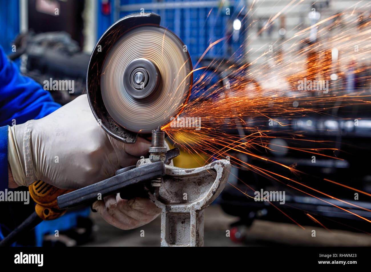 A close-up of a car mechanic using a metal grinder to cut a car silent ...