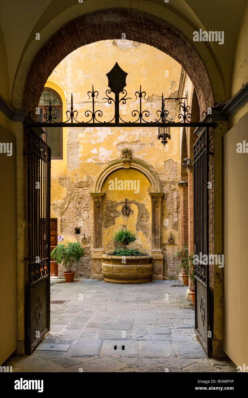 view through the gate into an typical italian patio with a fountain ...