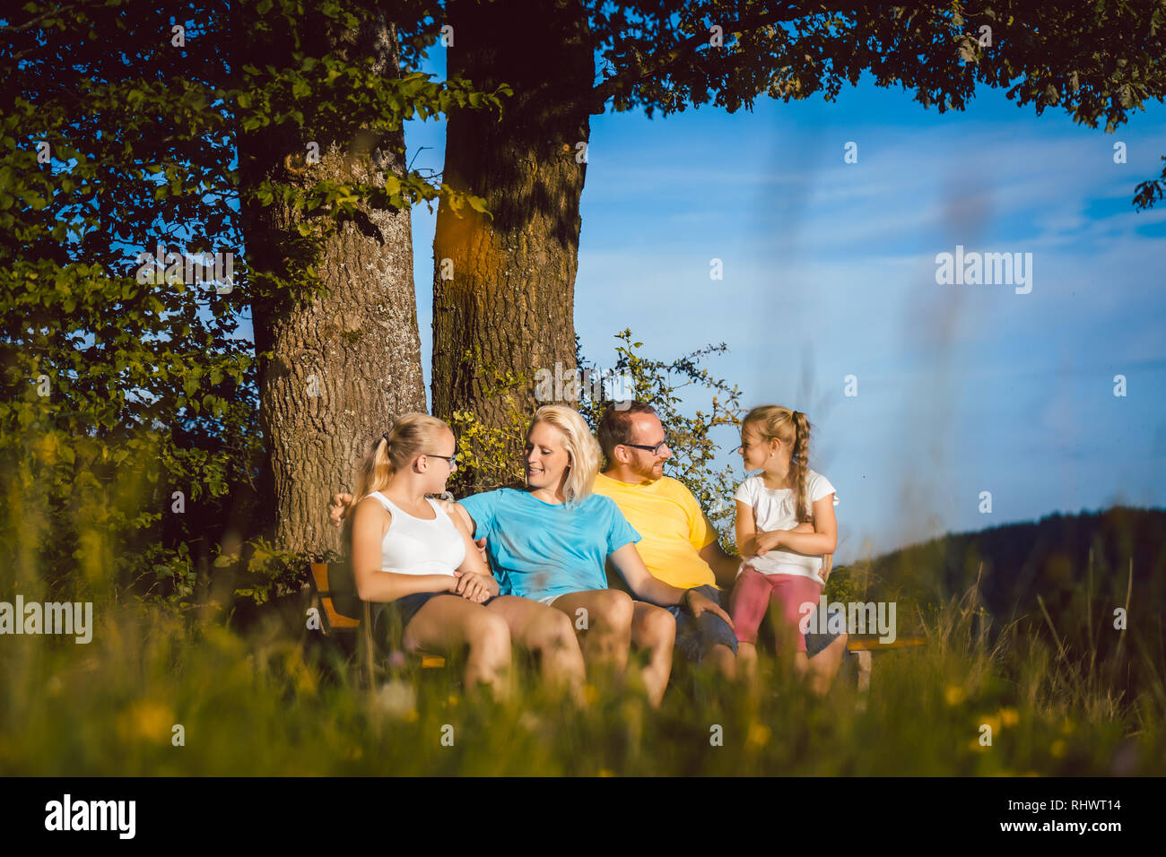 Family resting on bench during a long walk in summer Stock Photo - Alamy