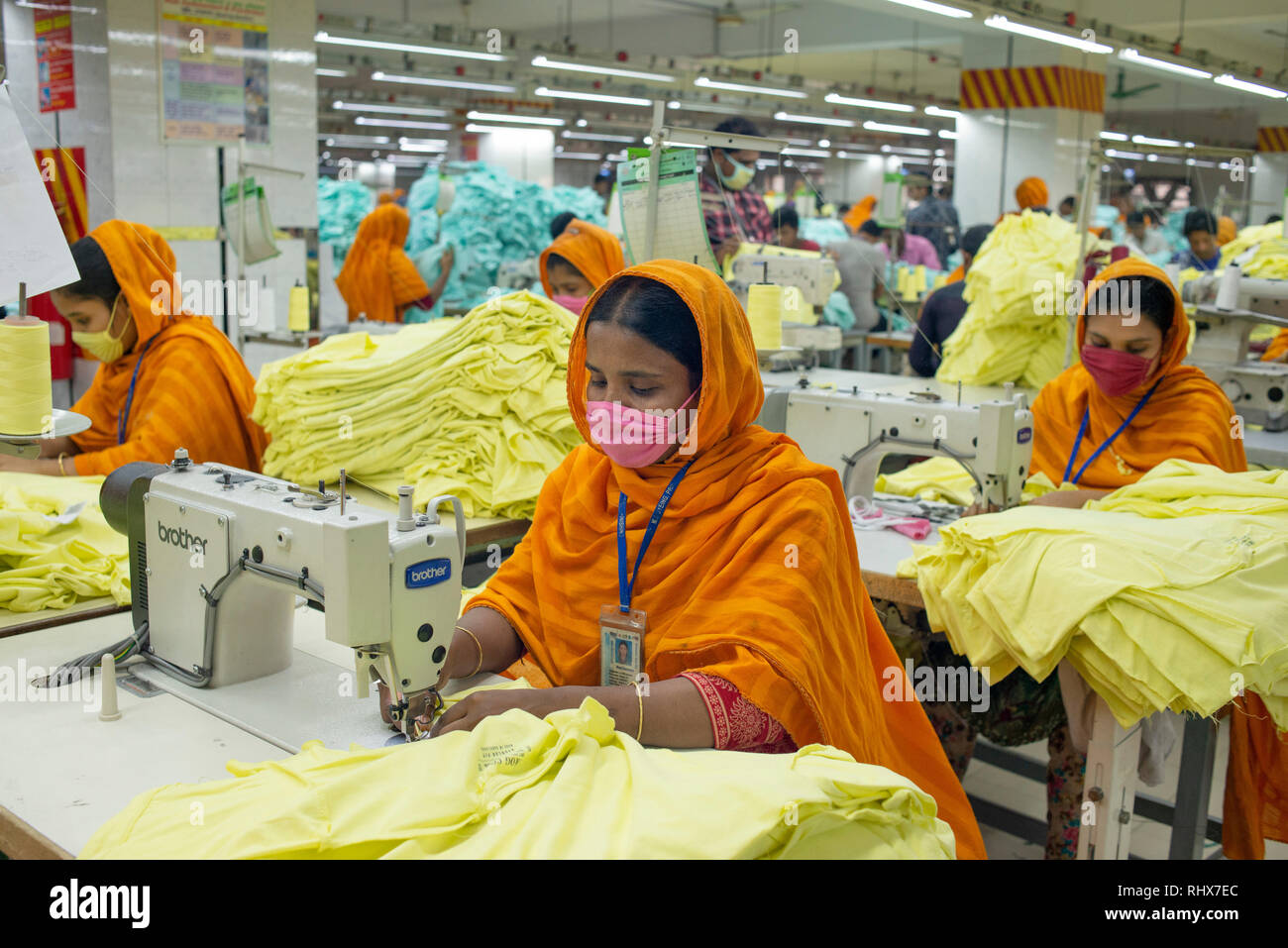 Garments workers are seen working in a sewing and finishing section ...