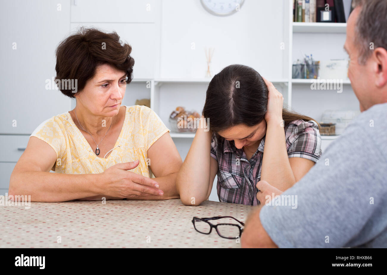 Woman sitting and looking negative while talking with senior parents at ...