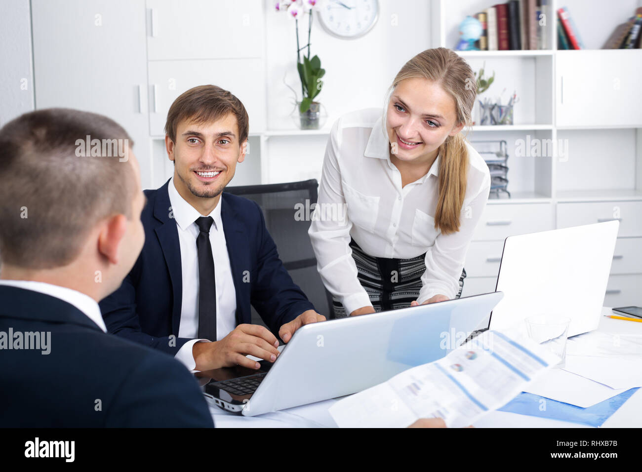 Smiling business male and female assistants in formalwear holding paper ...
