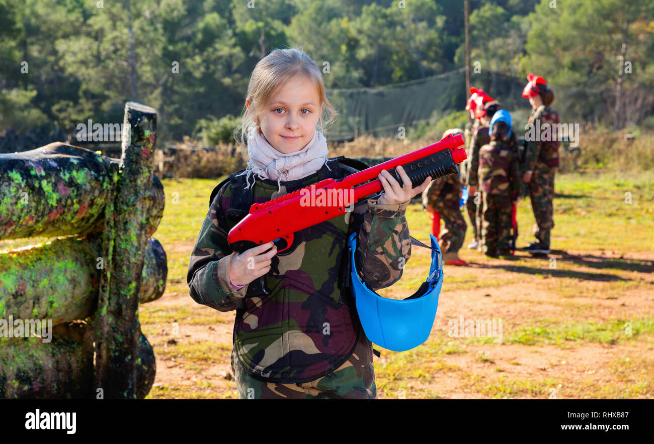 Cheerful smiling teen girl wearing uniform and holding gun ready for ...