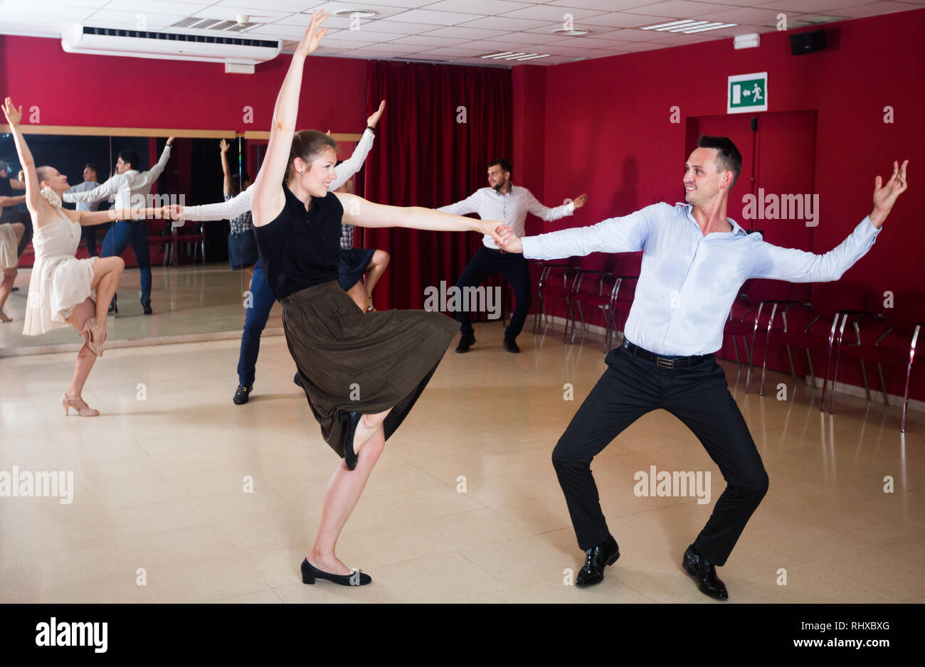 Adult dancing couples enjoying active boogie-woogie in modern studio ...