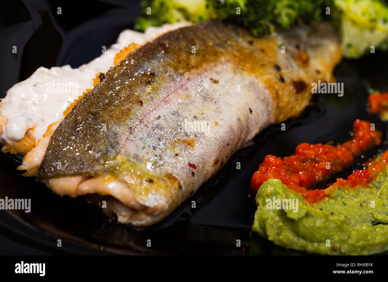 Healthy eating. Grilled fillets of steelhead trout served on black dish ...