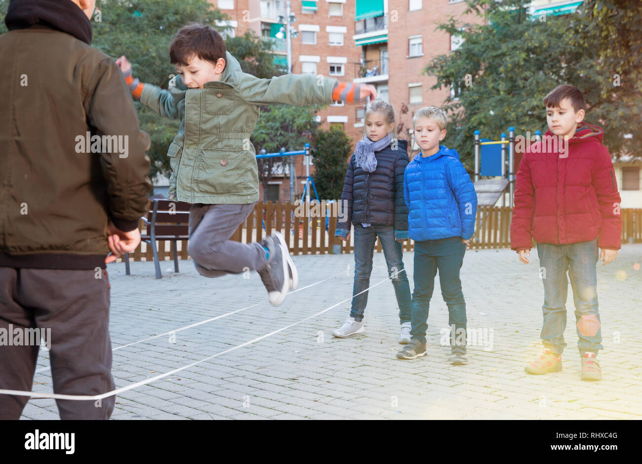 Children active games. Interested happy kids playing chinese jump rope ...