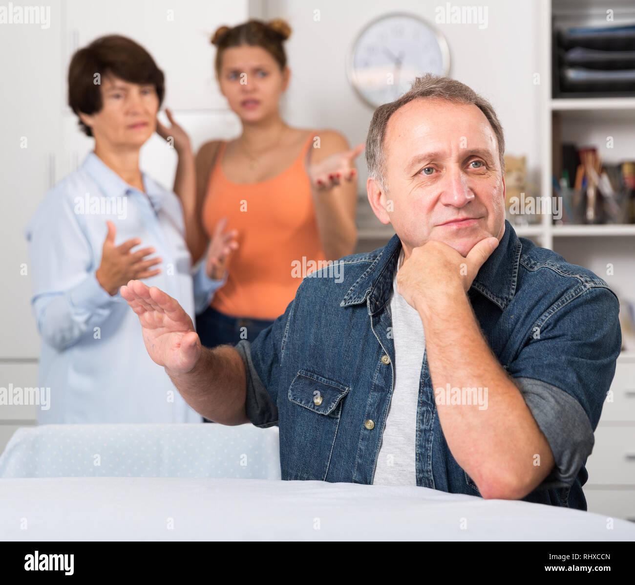Woman and her daughter are sympathying their sad father who is sitting ...