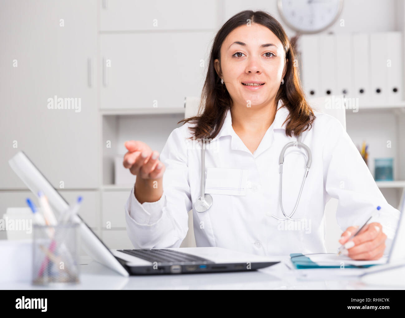 Girl doctor in uniform is writing papers behind laptop in hospital ... Girl doctor in uniform is writing papers behind laptop in hospital ...