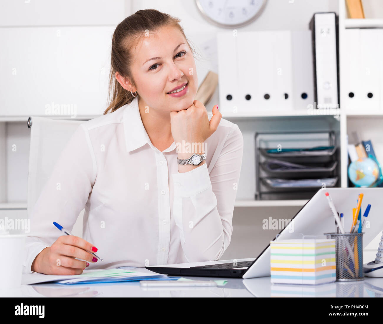 Young woman is posing while working behind laptop in the office Stock ...