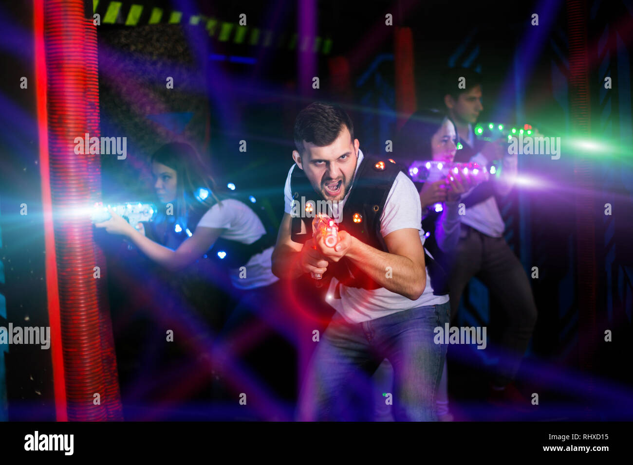 Portrait of excited guy laser tag player with laser pistol in room with ...