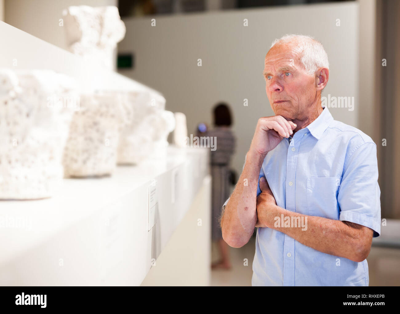 Attentive mature man observing sculptures exhibition in art museum ...
