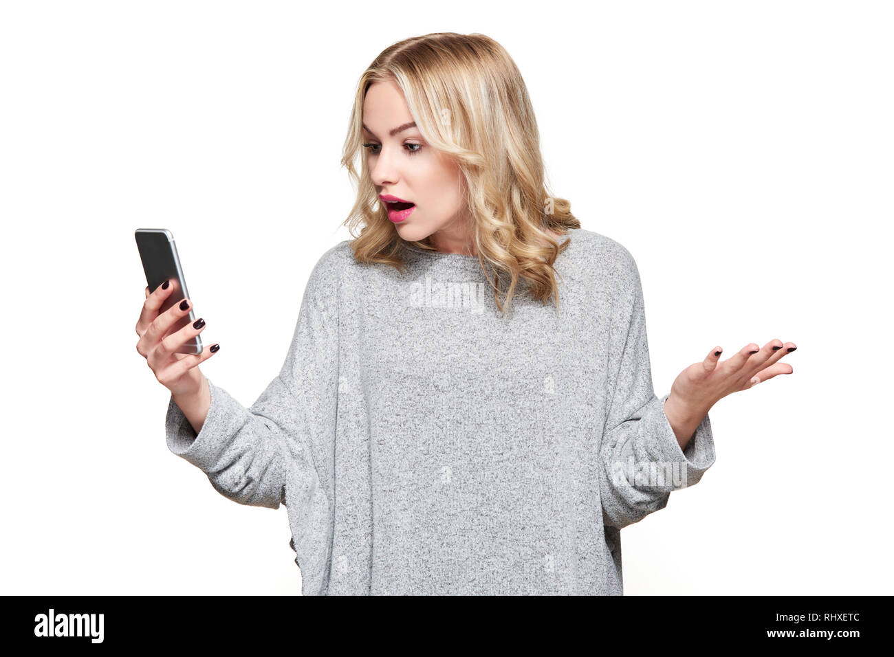 Shocked angry young woman looking at her mobile phone in disbelief ...