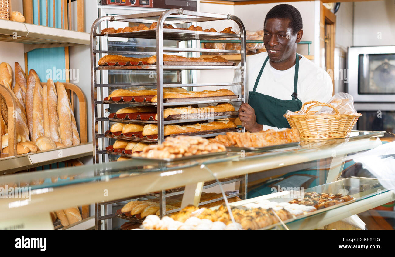 Skillful African American baker working in small bakery, carrying fresh ...