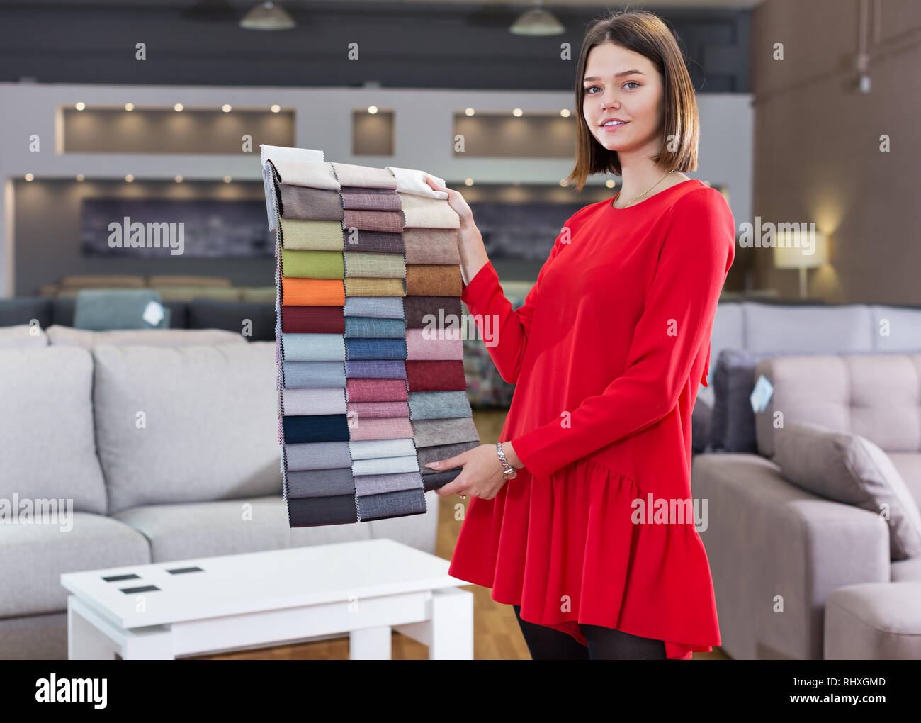 Friendly sales consultant demonstrating samples of upholstery fabric in ...