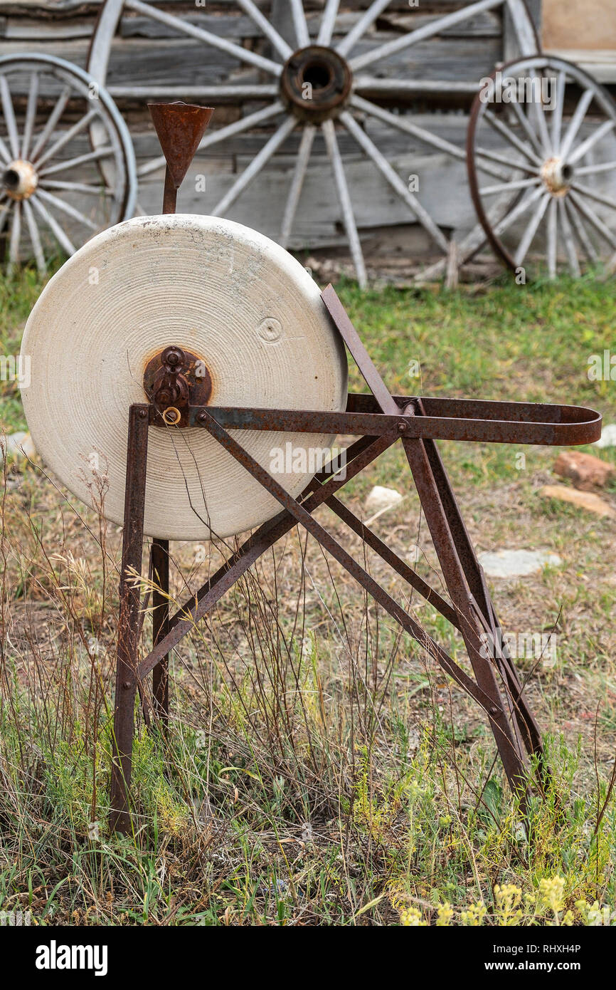 An old stone grinding wheel and wagon wheels in an old museum in ...