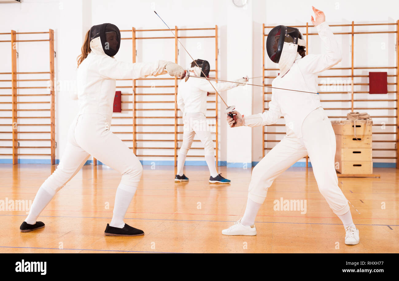 Two women fencers practicing a techniques in duel at fencing sparring ...