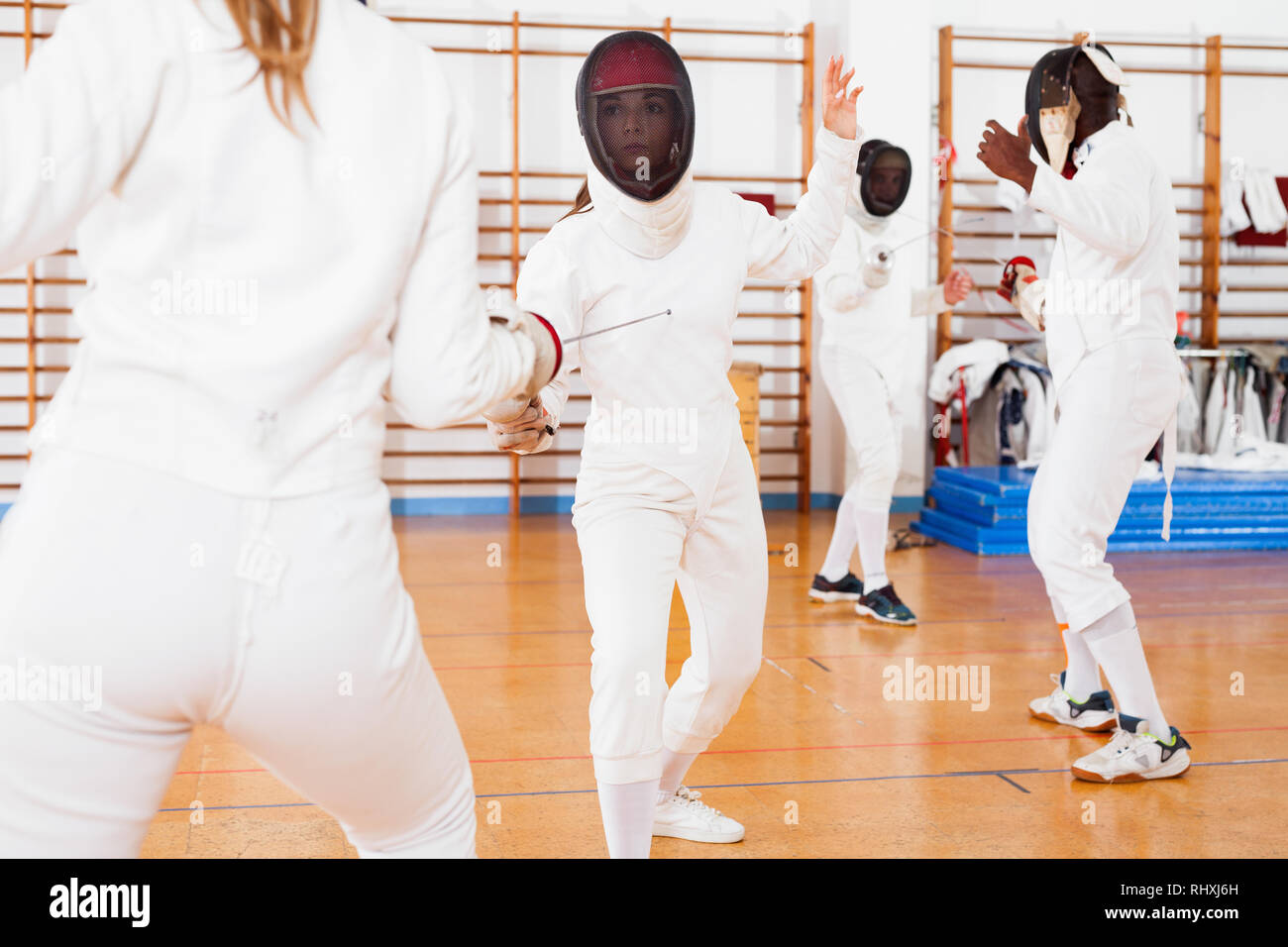 Two glad cheerful smiling female fencers exercising movements in duel ...