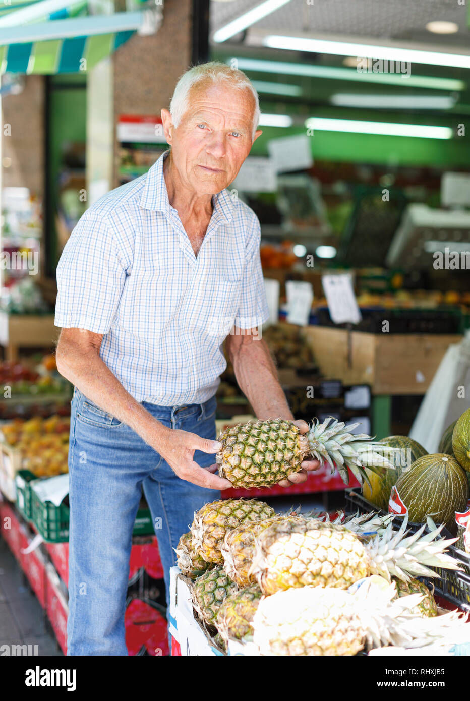 Positive senior man searching for fresh fruits in greengrocery Stock ...