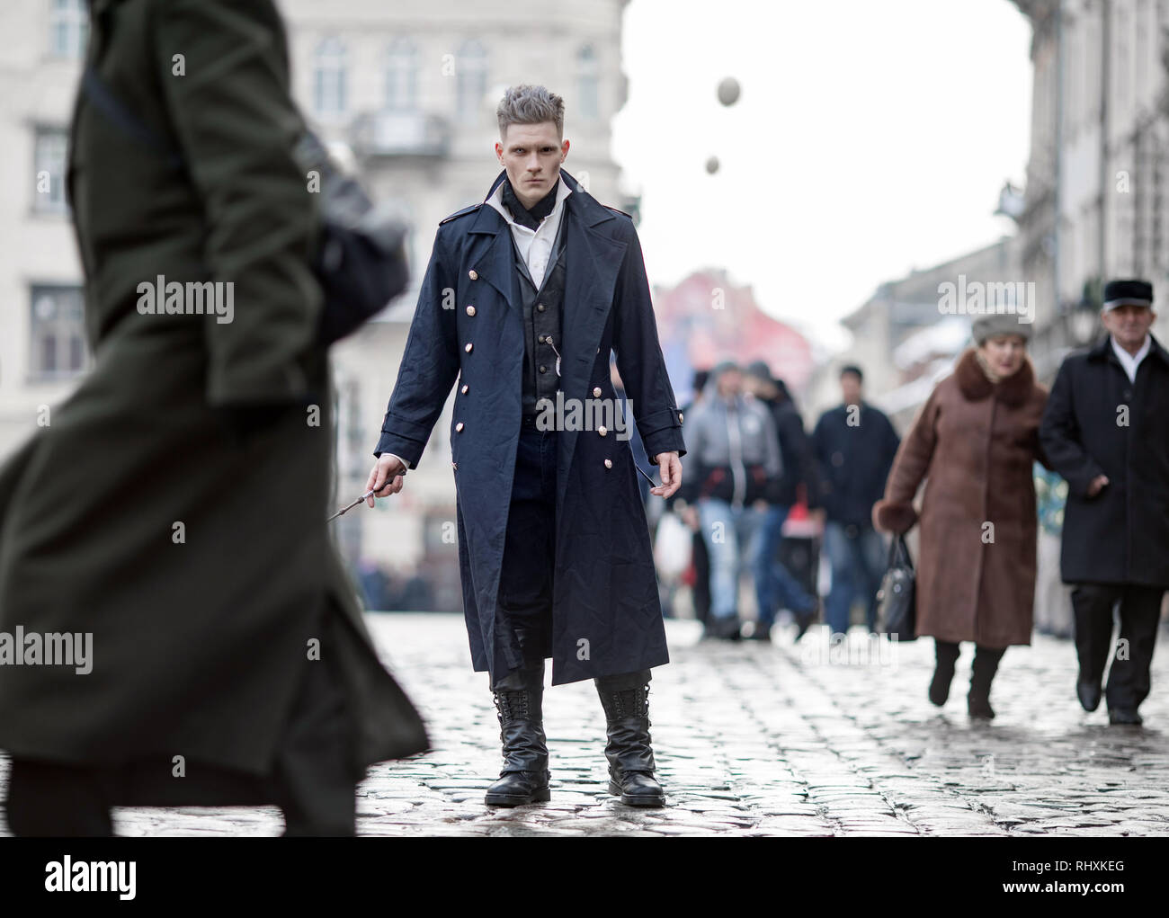 Young man in image of black magician walks on city street with magic ...