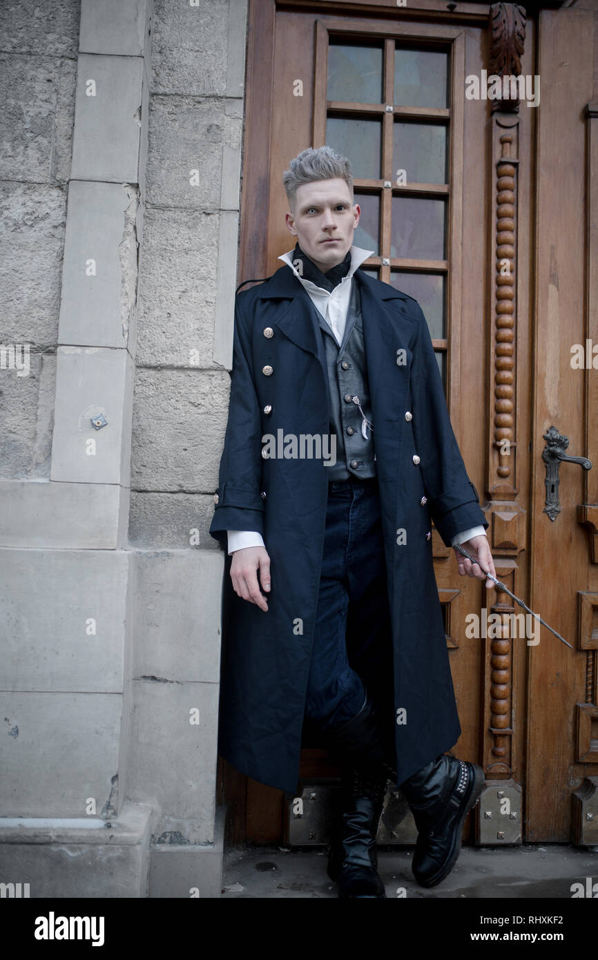 Young man in image of black magician walks on city street with magic ...