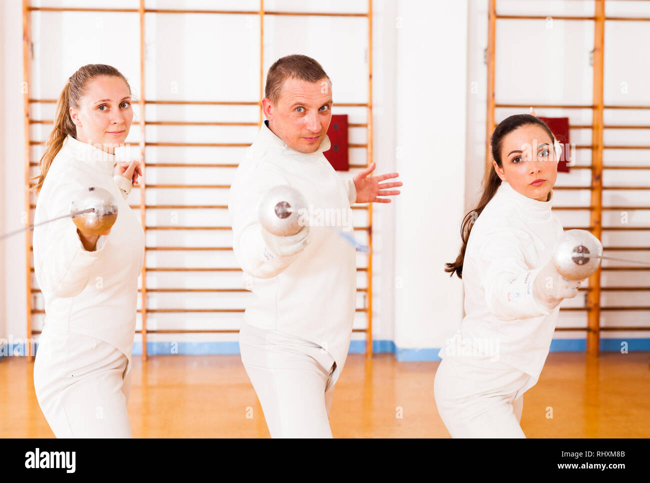 Man and women fencers practicing movements together at fencing workout ...