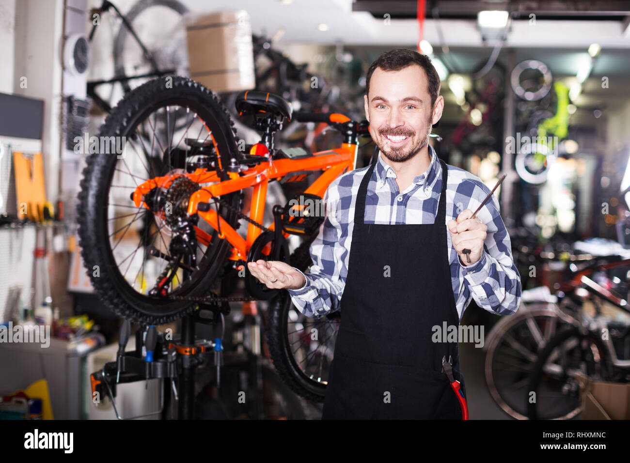 Young man working as mechanic for assembly of bicycles in store ...