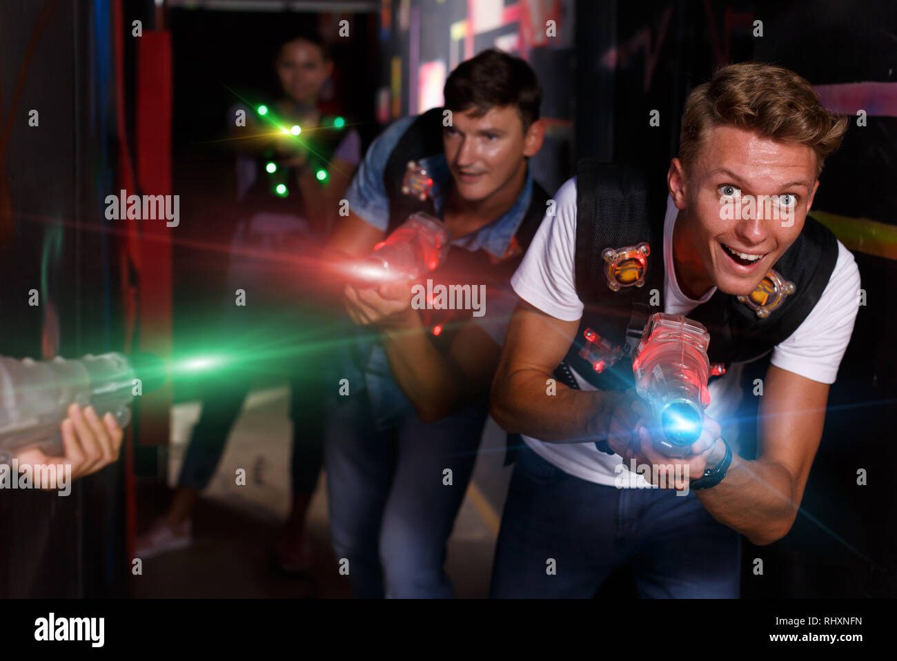 Group portrait of joyful emotional people with laser guns playing laser ...