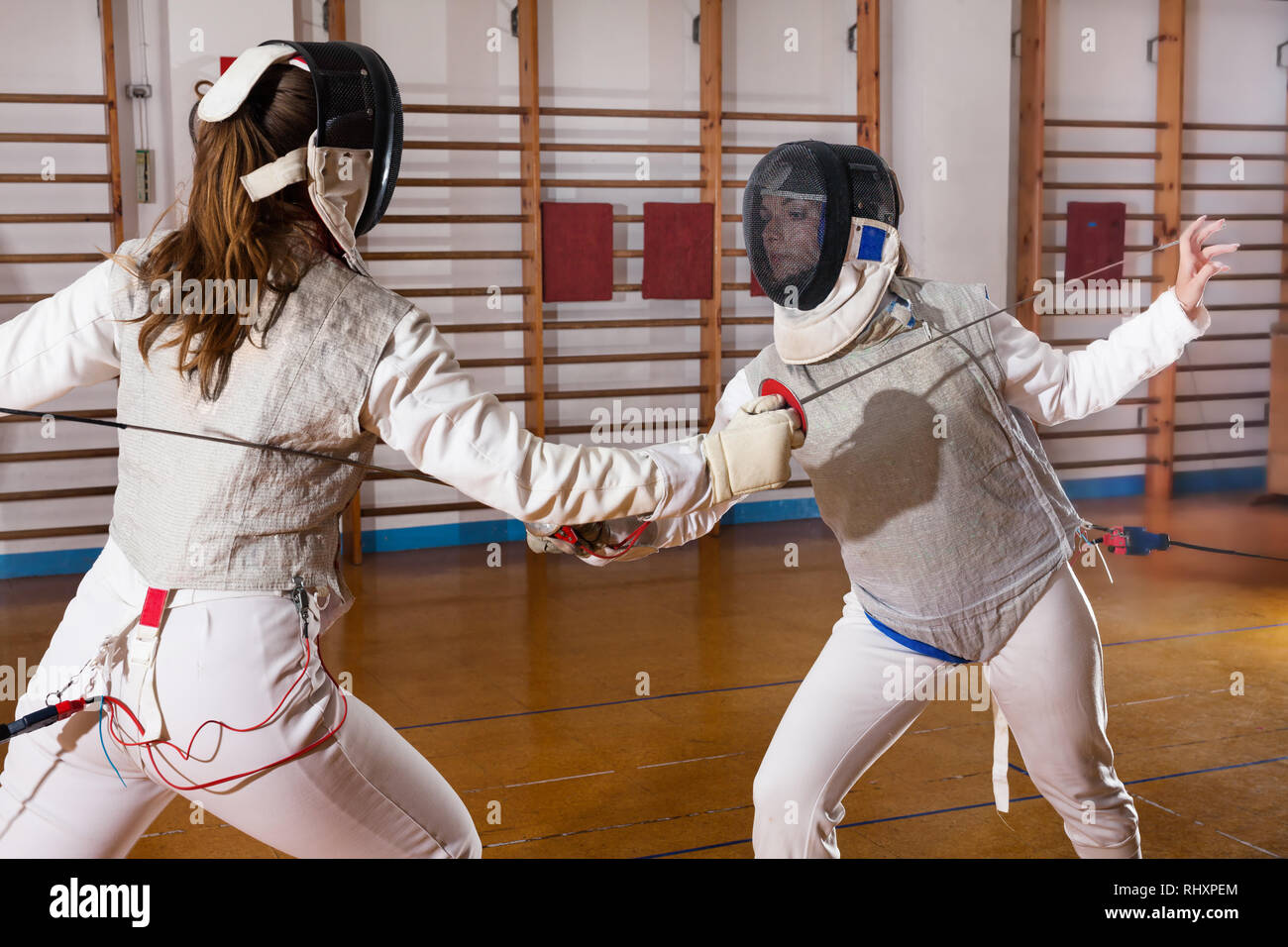 Portrait of female athletes practicing movements at fencing workout ...